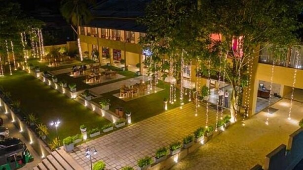 Pátio de hotel com área de estar ao ar livre, piscina e luzes de fada.