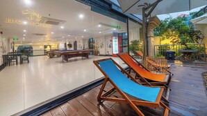 Uma área de piscina com espreguiçadeiras, mesa de bilhar e bar.