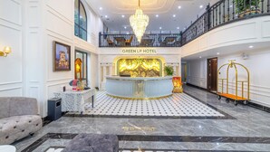 Um saguão de hotel com balcão de recepção, lustre, varanda e mesa de check-in.