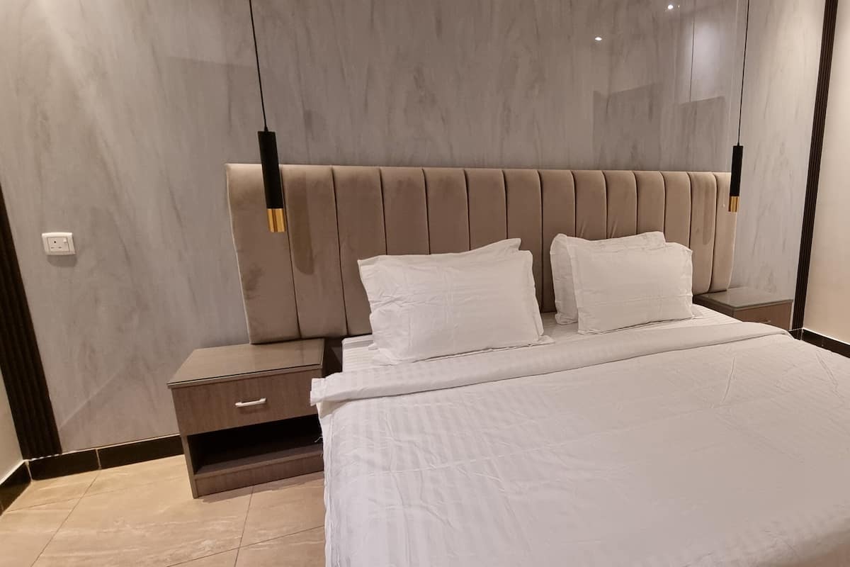 Um quarto moderno com uma cama grande, uma mesa de cabeceira, um aparador e um espelho.
