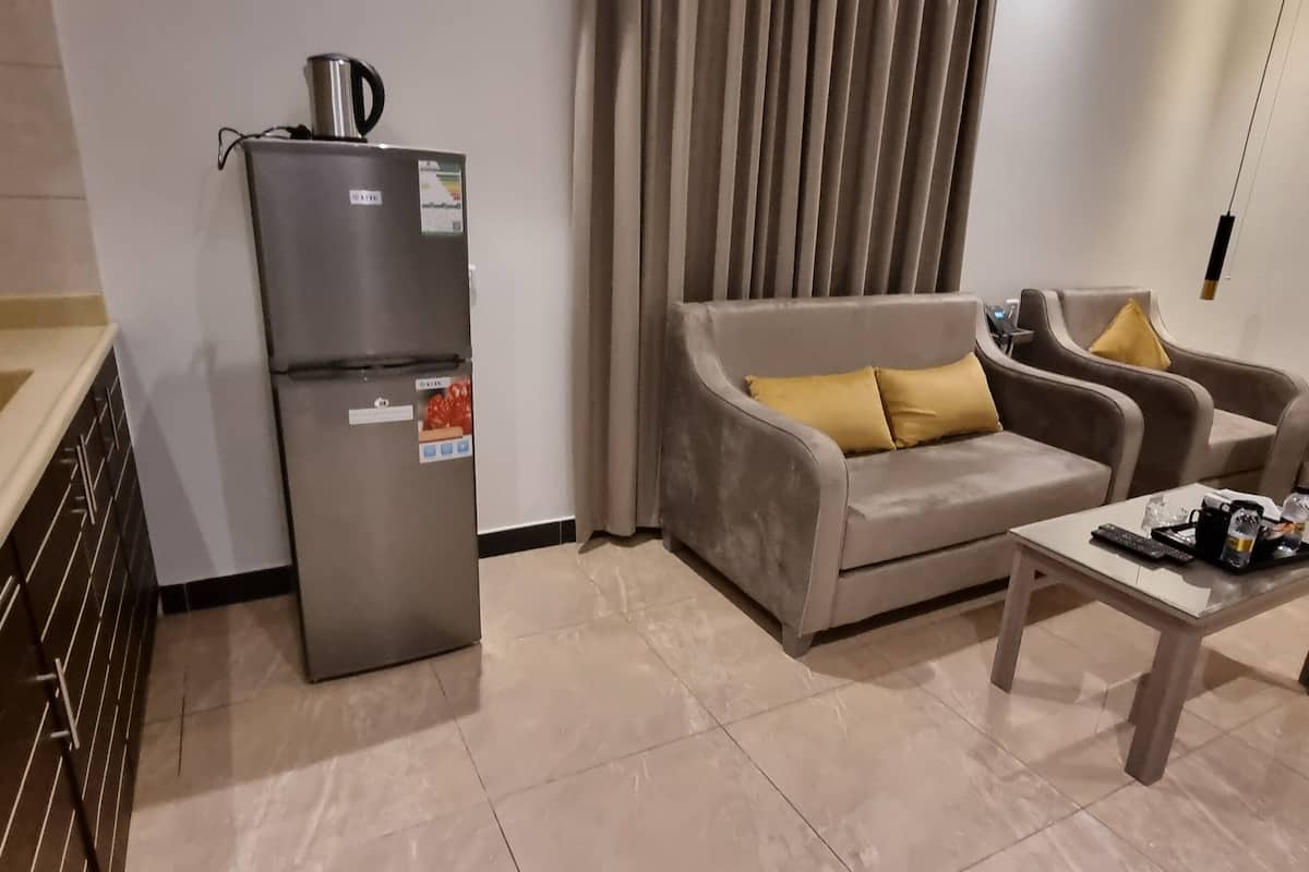 Uma sala de estar moderna com um conjunto de sofá, uma mesa de centro e uma geladeira.