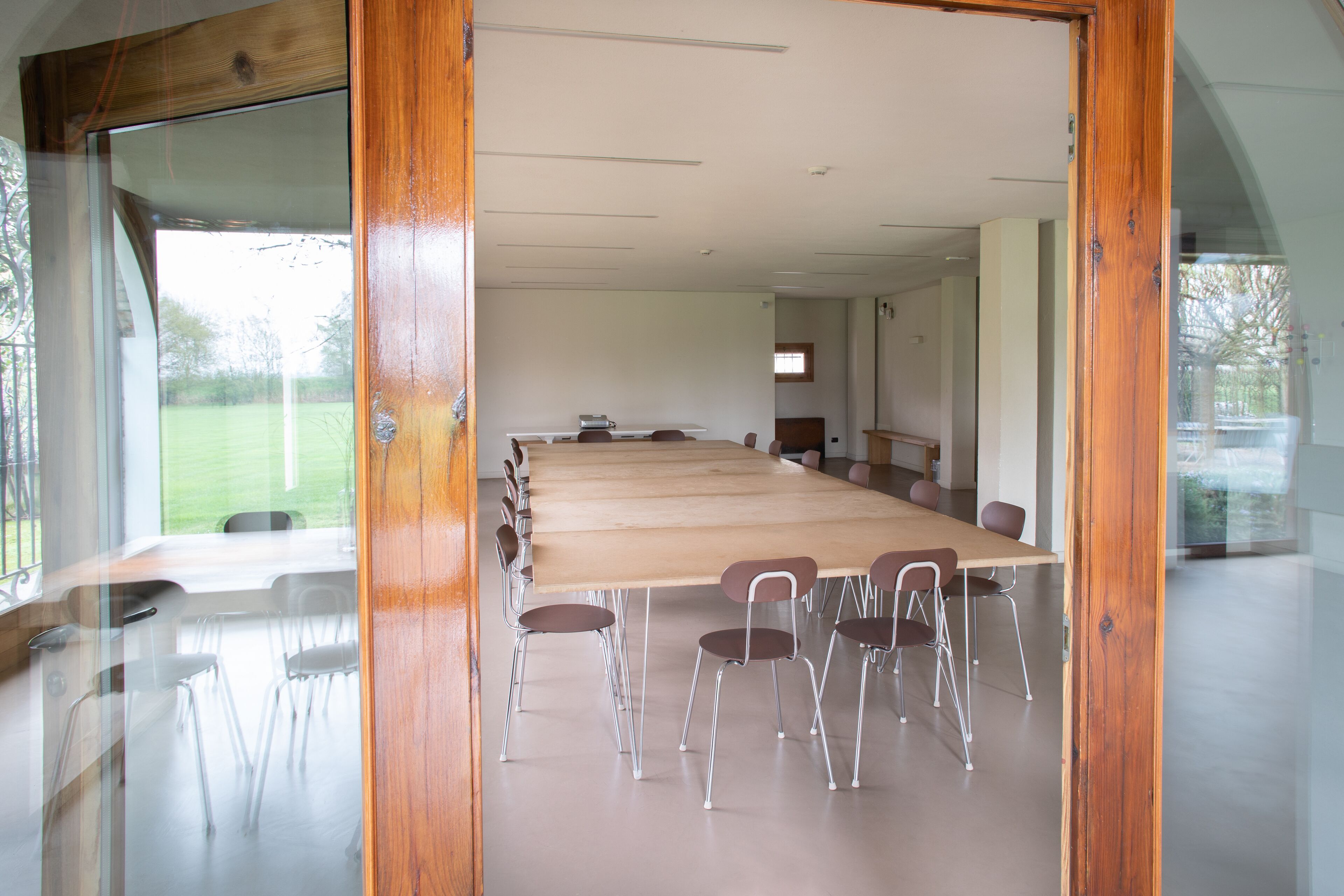 Uma sala de conferências com uma mesa comprida, várias cadeiras e um painel de vidro.