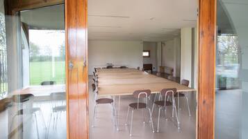 Uma sala de conferências com uma mesa comprida, várias cadeiras e um painel de vidro.