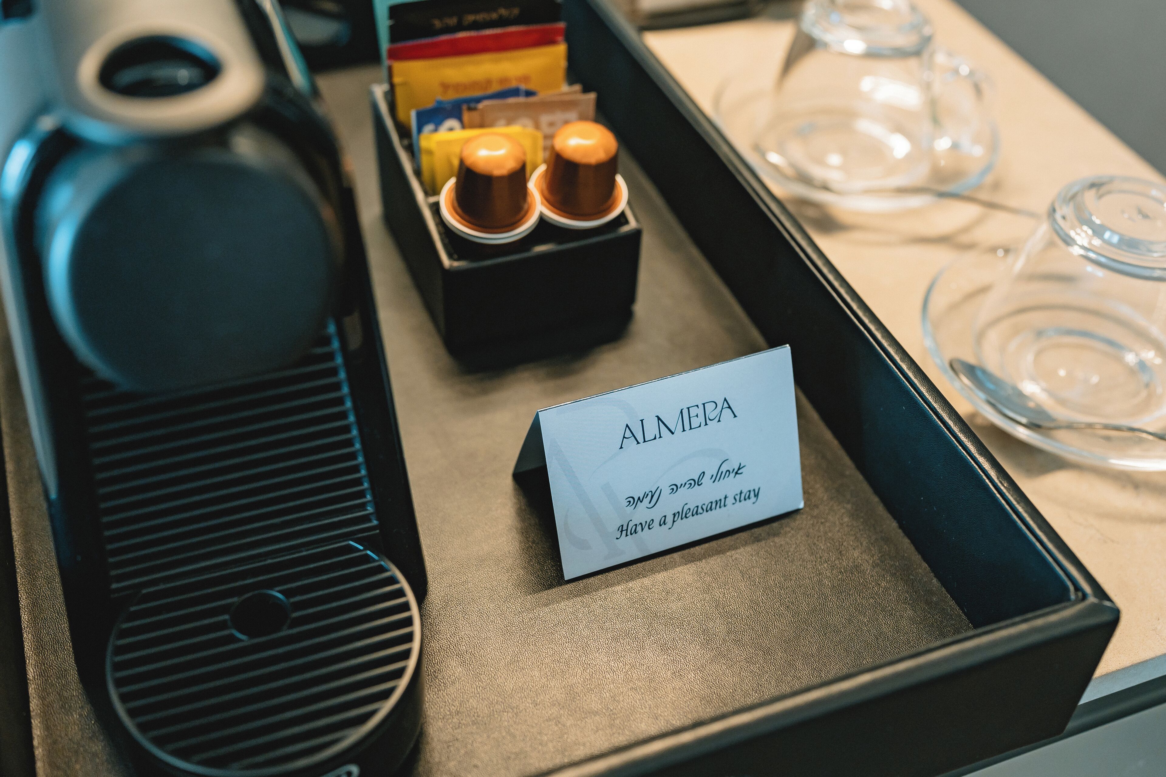 Uma bandeja com cartão de nome indicando "ALMERA" e a mensagem "Este é o seu quarto. Tenha uma estadia agradável."