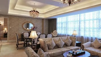 Uma sala de estar ampla com um amplo sofá, uma área de jantar com cadeiras e uma mesa, e um candelabro.