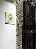 Mural de pedra com portão de metal e placa com brasão.