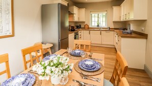 Uma cozinha moderna com uma ilha central, armários de madeira e uma área de refeições posta para uma refeição.