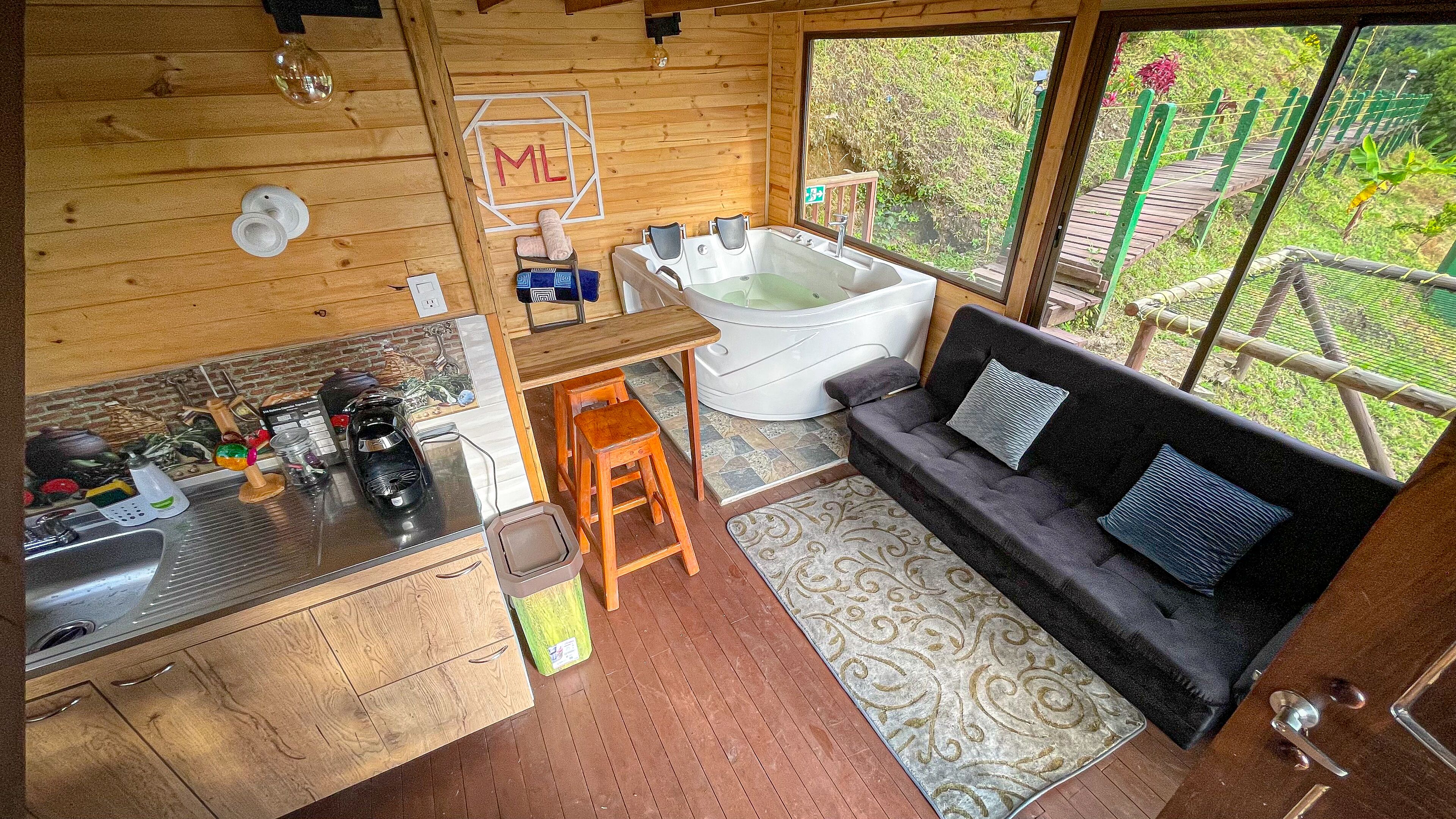 Interior acolhedor de uma cabana com cozinha compacta, uma banheira grande e um sofá.