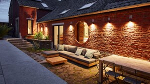 Uma casa moderna com fachada de tijolos, um banco de madeira, um sofá e uma mesa.