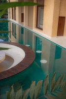 Uma piscina com borda curva, uma janela e uma porta ao fundo.