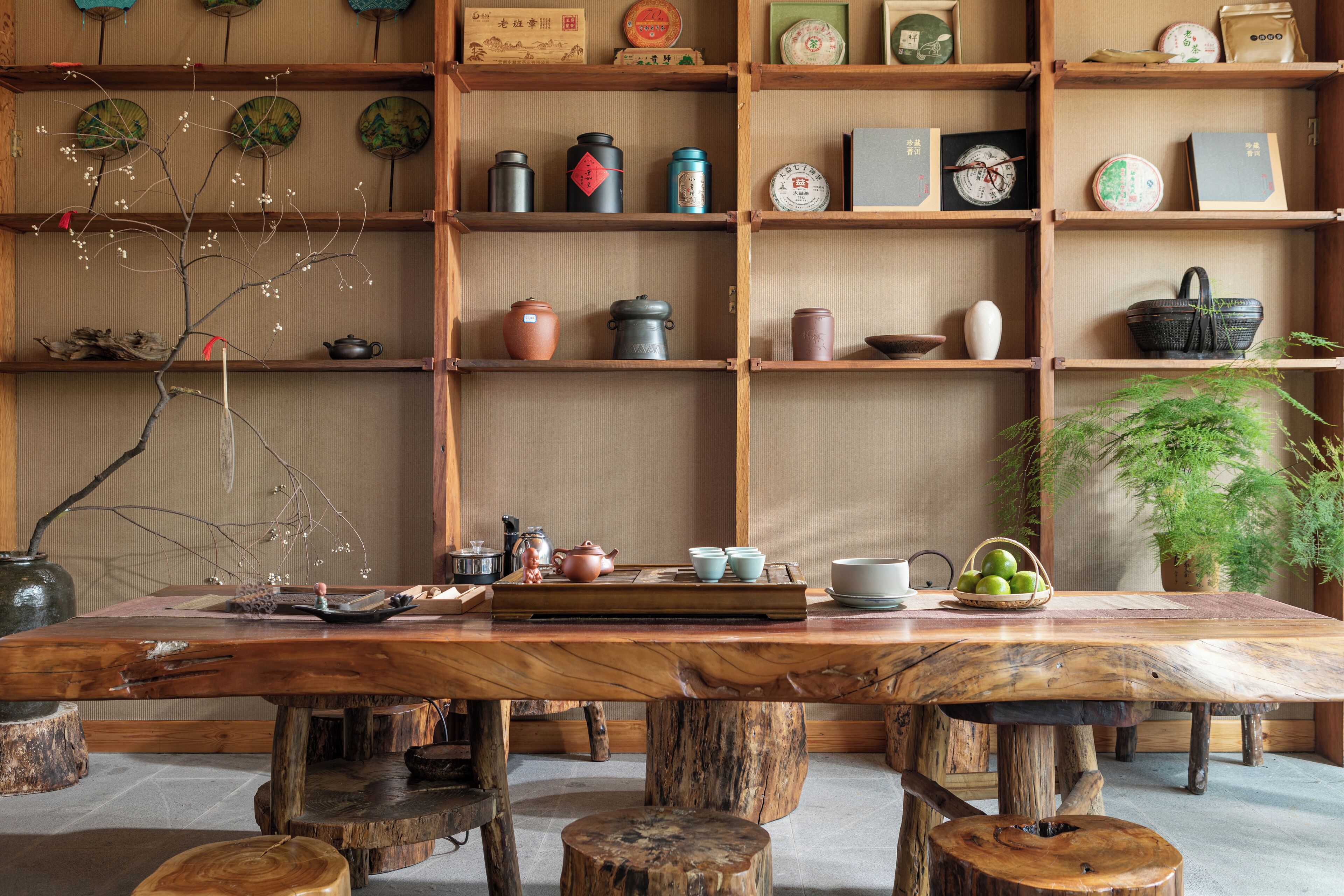 Um quarto japonês tradicional com tatames, uma mesa de madeira baixa e prateleiras com diversos objetos de cerâmica e tecidos.