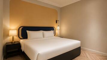 Quarto de hotel com cama, mesa de cabeceira, abajur e luminária na parede.