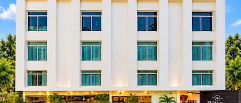 Um hotel moderno com fachada plana, amplas janelas e um jardim no terraço.