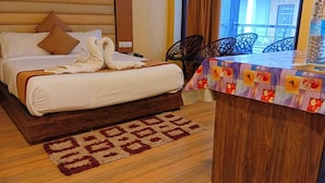 Quarto de hotel com cama de madeira, tapete estampado e mesa com toalha de mesa colorida.