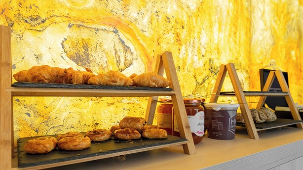 Um buffet de café da manhã com pães e acompanhamentos à mostra.