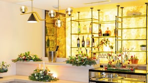 Uma área de bar com prateleiras de garrafas, um caixa registradora e arranjos florais decorativos.