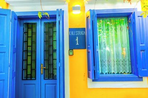 Um edifício com portas azuis e uma janela com cortinas de renda.