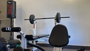 Uma academia com um banco de supino, uma estrutura para agachamento e anilhas.