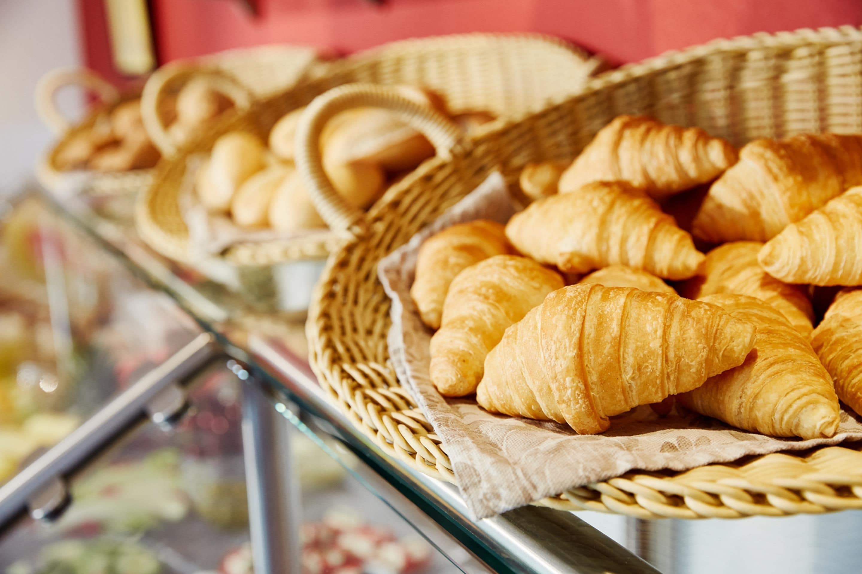 Exposição de diversos pastéis, incluindo croissants, em cestas de vime.
