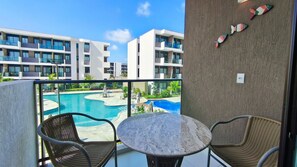 Varanda com vista para uma piscina, duas cadeiras de vime e uma mesa redonda.