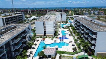 Resort com várias construções, uma piscina central e vista para o oceano.
