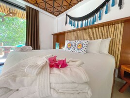 Quarto de hotel com cama, toalhas e almofada decorativa.