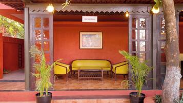 Uma área de recepção com um banco de madeira, duas cadeiras, uma mesa e um quadro na parede.