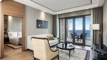 Quarto de hotel moderno com uma varanda grande, um sofá branco, uma poltrona bege e uma mesa de jantar com um vaso.