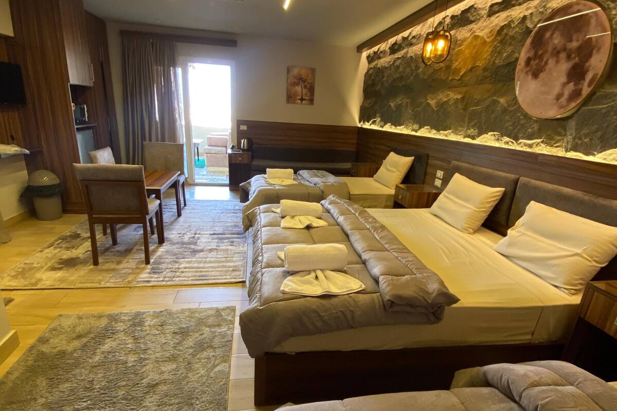 Quarto de hotel moderno com uma cama grande, uma mesa e um espaço de estar.