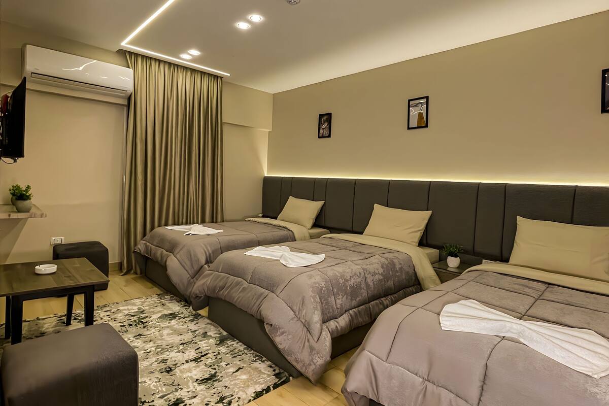 Quarto de hotel moderno com duas camas, uma escrivaninha e um ar condicionado.