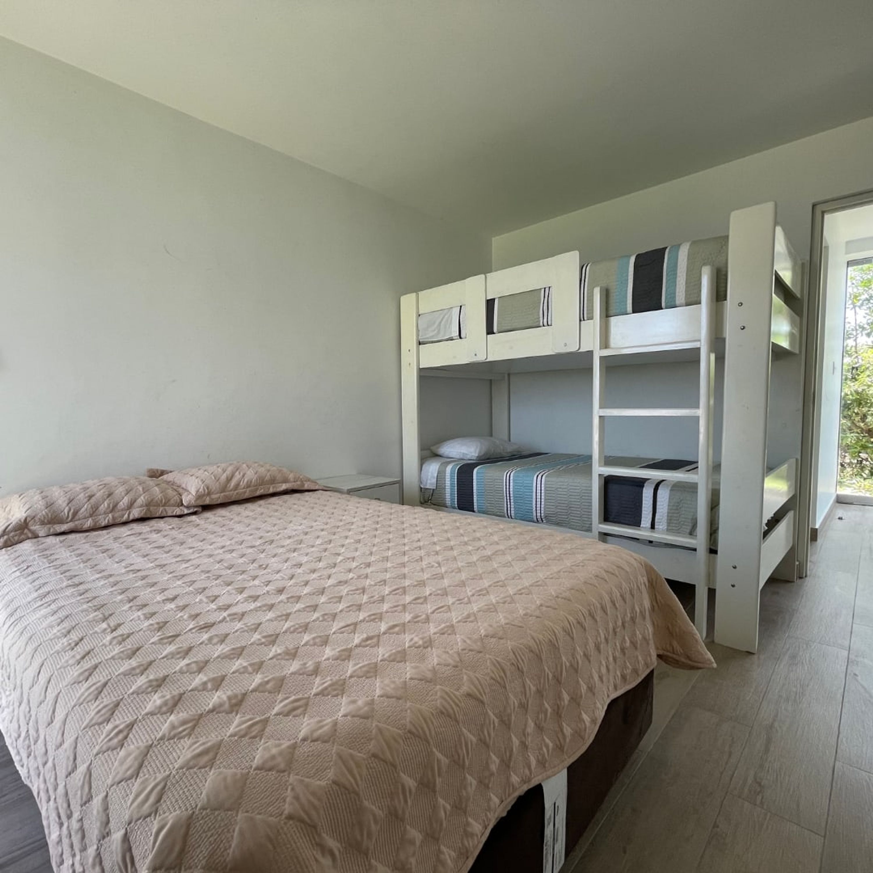 Quarto com uma cama grande, duas beliches e um guarda-roupa.