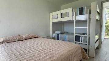 Quarto com uma cama grande, duas beliches e um guarda-roupa.