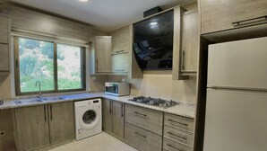 Uma cozinha moderna com máquina de lavar embutida, micro-ondas, fogão a gás e frigorífico.