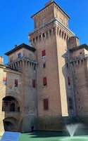 Um edifício histórico com uma torre central e janelas em arco.
