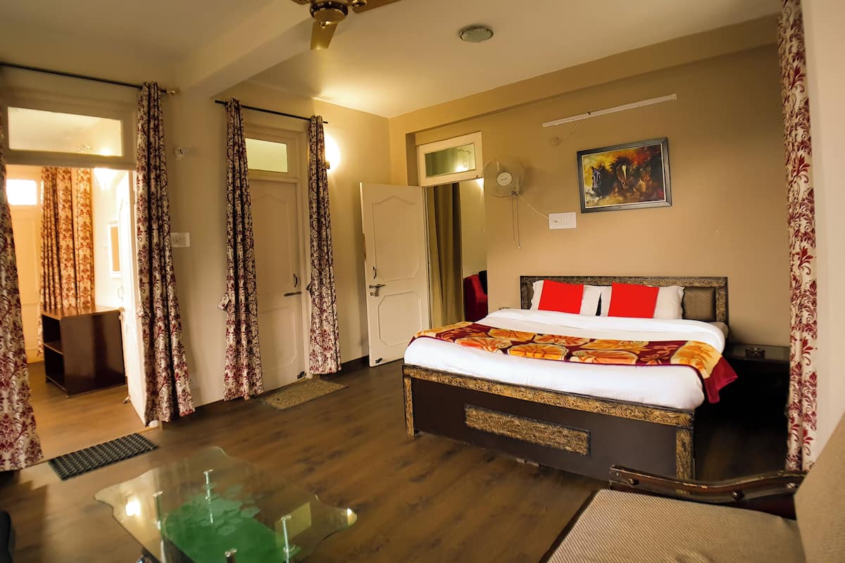 Quarto de hotel com cama, ventoinha no teto, quadro e chão de madeira.