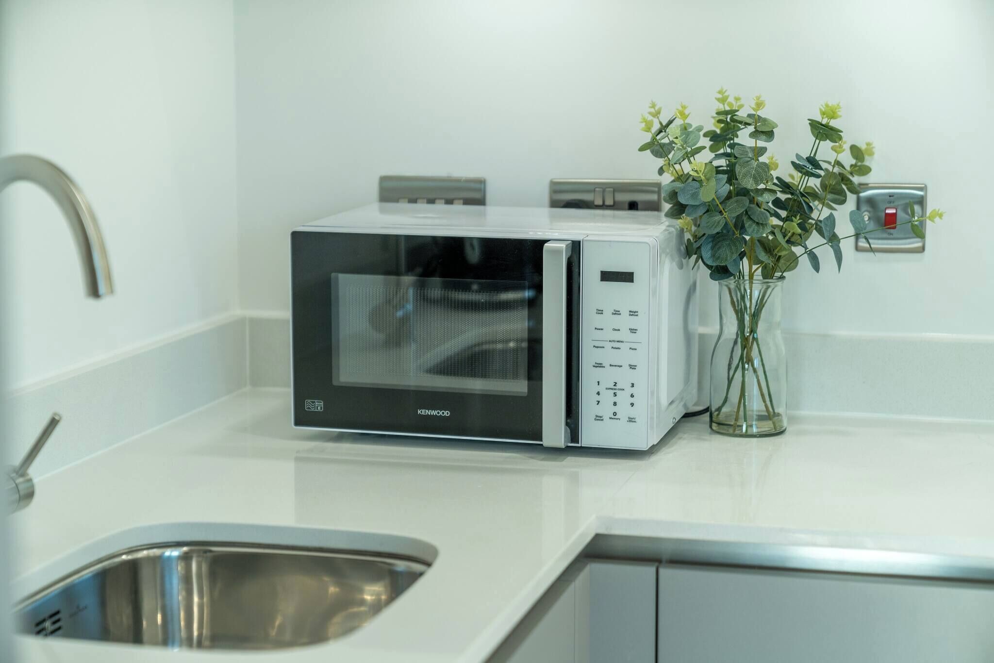 Um forno de micro-ondas com visor digital, painel de comandos e a marca na frente.