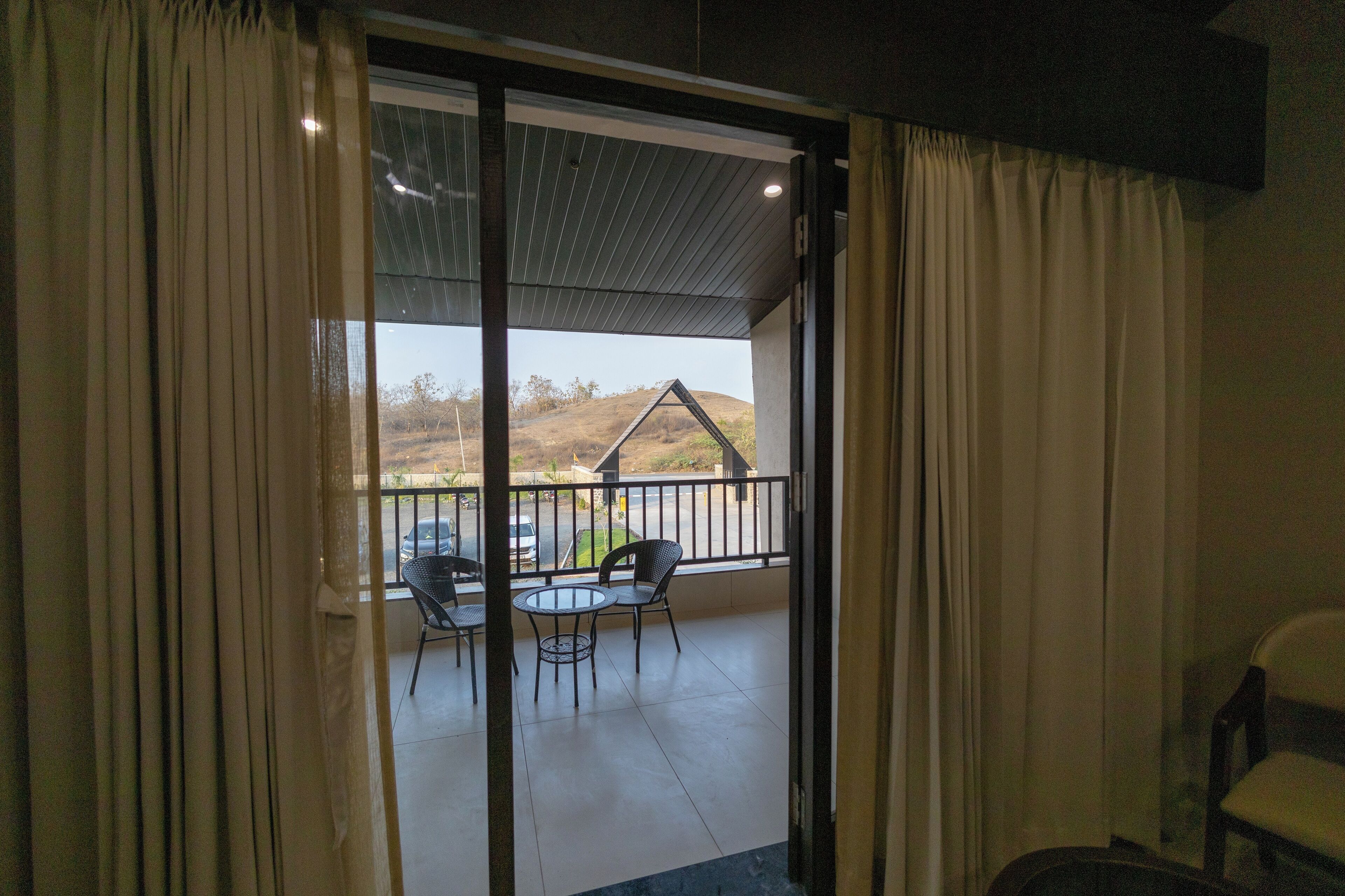 Quarto com porta de correr de vidro que dá para uma varanda externa com mesa e cadeiras.