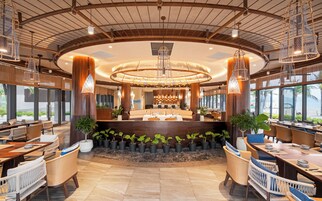 Um restaurante espaçoso com balcão central, diversas áreas de estar e amplas janelas com vista.