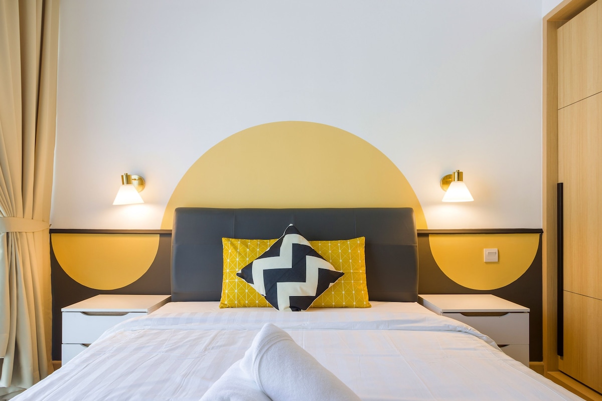 Quarto de hotel com uma cama, mesa de cabeceira, abajur e luminária na parede.