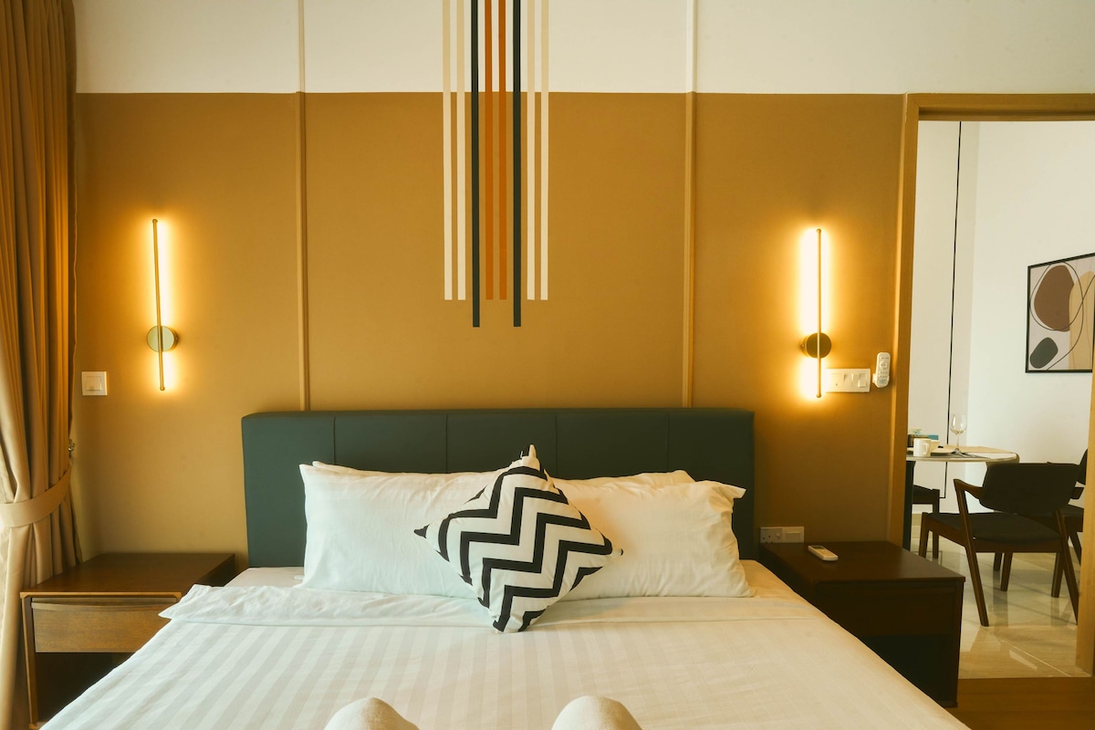 Quarto de hotel com cama, mesas de cabeceira, escrivaninha e uma cadeira.