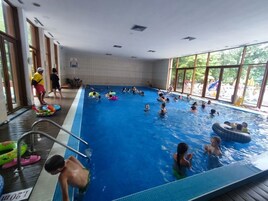 Uma piscina interior com várias pistas de natação, um trampolim e uma cadeira de salva-vidas.