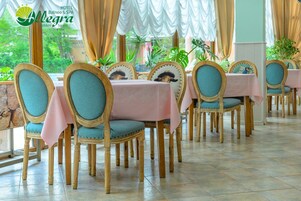 Restaurante com mesas cobertas por toalhas cor-de-rosa e cadeiras com estofamento azul.