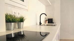 Cozinha moderna com bancada preta, pia de aço inoxidável e duas plantas em vasos.