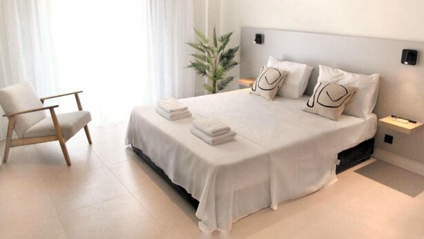 Quarto moderno com uma cama grande, uma cadeira e uma mesa de cabeceira.