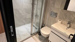 Uma casa de banho moderna com cabine de duche em vidro, sanita e lavatório com espelho em cima.