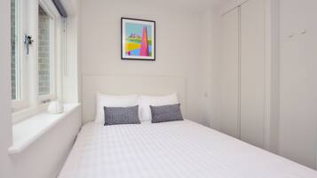 Quarto com cama, janela, quadro e guarda-roupa.