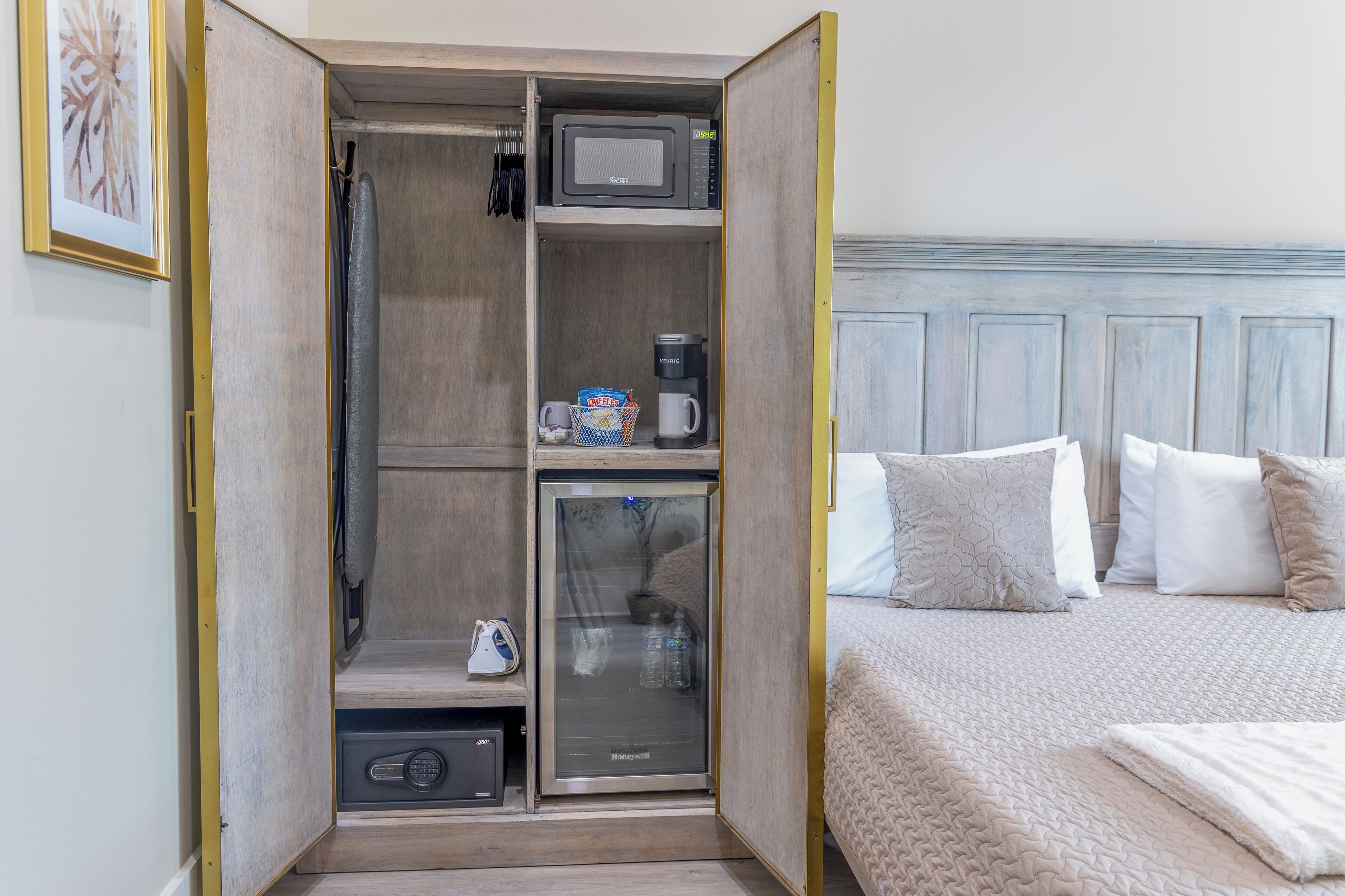 Quarto de hotel com cama, minibar, micro-ondas e máquina de café.