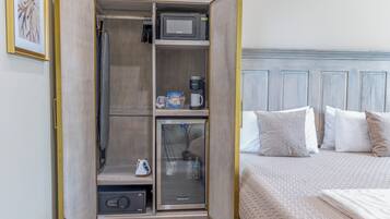 Quarto de hotel com cama, minibar, micro-ondas e máquina de café.