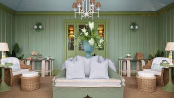 Um quarto com parede verde, cama com almofadas listradas, um lustre e duas mesas de cabeceira com abajures.