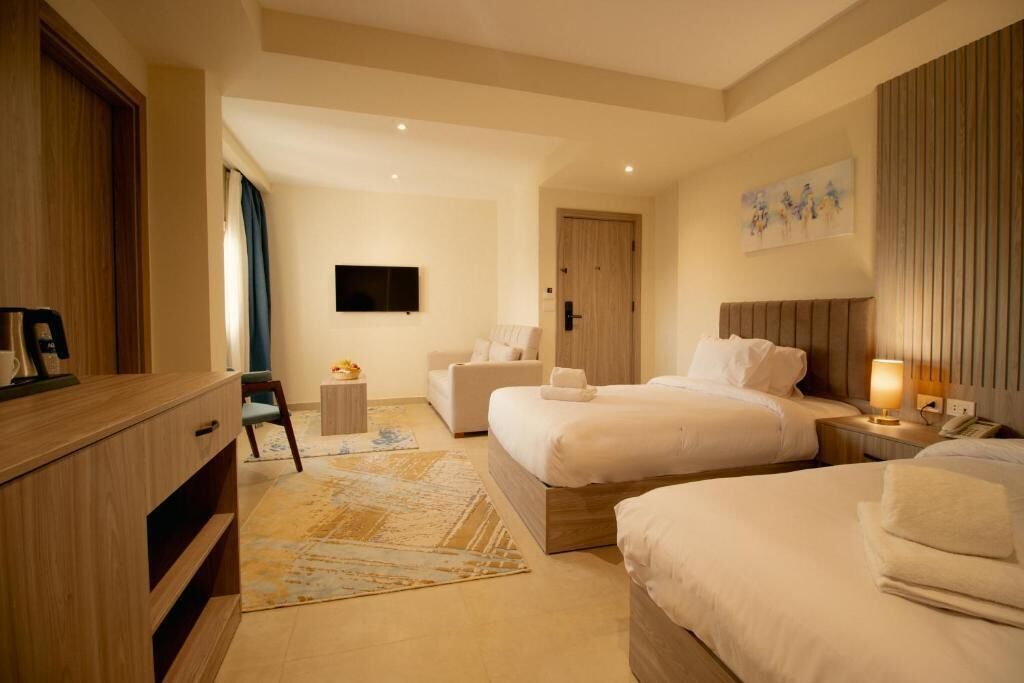 Quarto de hotel com duas camas, televisão, escrivaninha e uma cadeira.